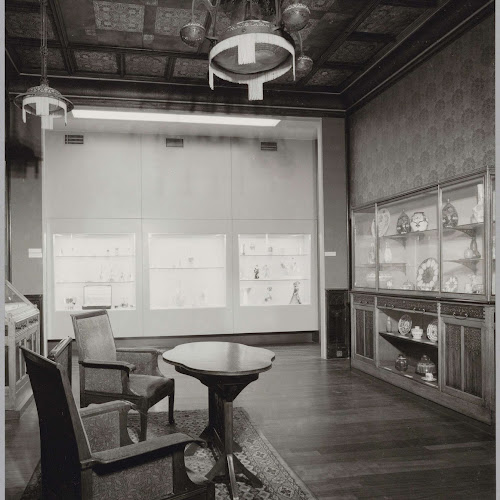 Zaal met muur- en plafondbetimmering, behang, stoelen, tafel, kasten ...